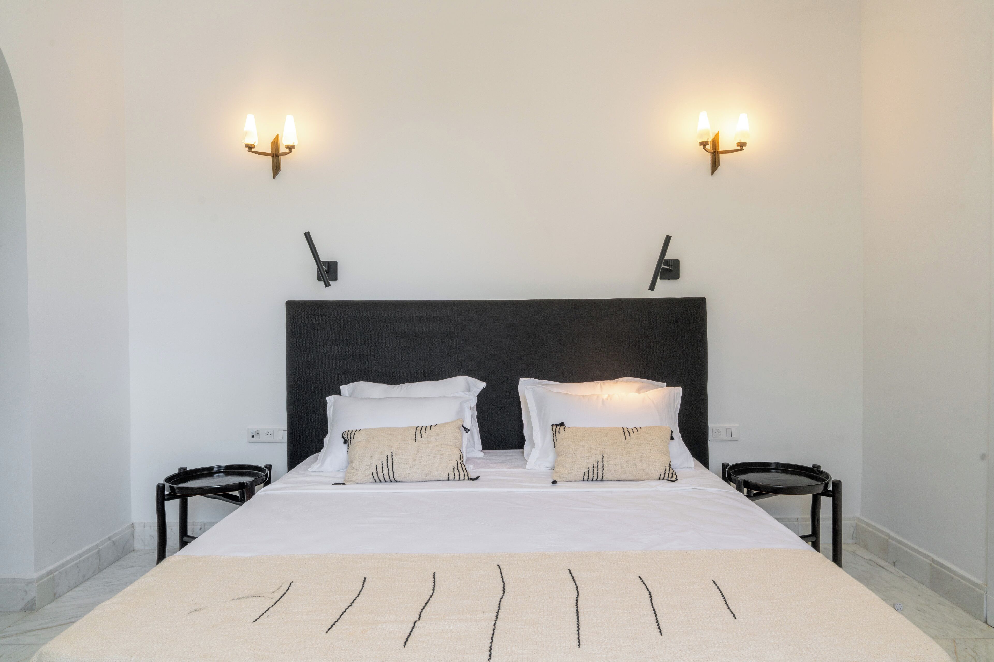 Quarto com uma cama grande, duas mesas de cabeceira e iluminação na parede.