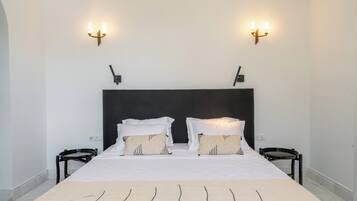 Quarto com uma cama grande, duas mesas de cabeceira e iluminação na parede.
