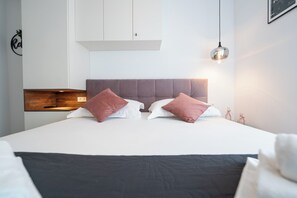 Quarto moderno com uma cama grande, cabeceira de madeira e luminária pendente.