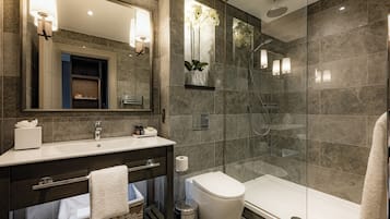 Uma casa de banho moderna com cabine de duche em vidro, lavatório branco e espelho grande.