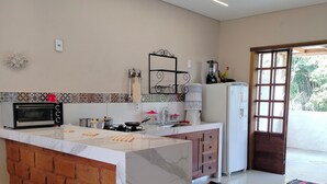 Cozinha moderna com ilha de mármore, micro-ondas embutido e frigorífico.