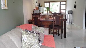 Uma sala de estar com sofá, mesa de jantar e cadeiras, cozinha e uma janela grande.