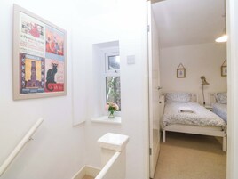 Quarto com cama, janela, pôster fixado na parede e mesinha de cabeceira.