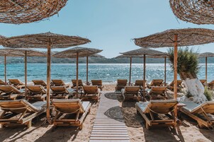 Na praia, praia de areia branca, espreguiçadeiras, guarda-sóis de praia 