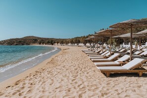 Na praia, praia de areia branca, espreguiçadeiras, guarda-sóis de praia 