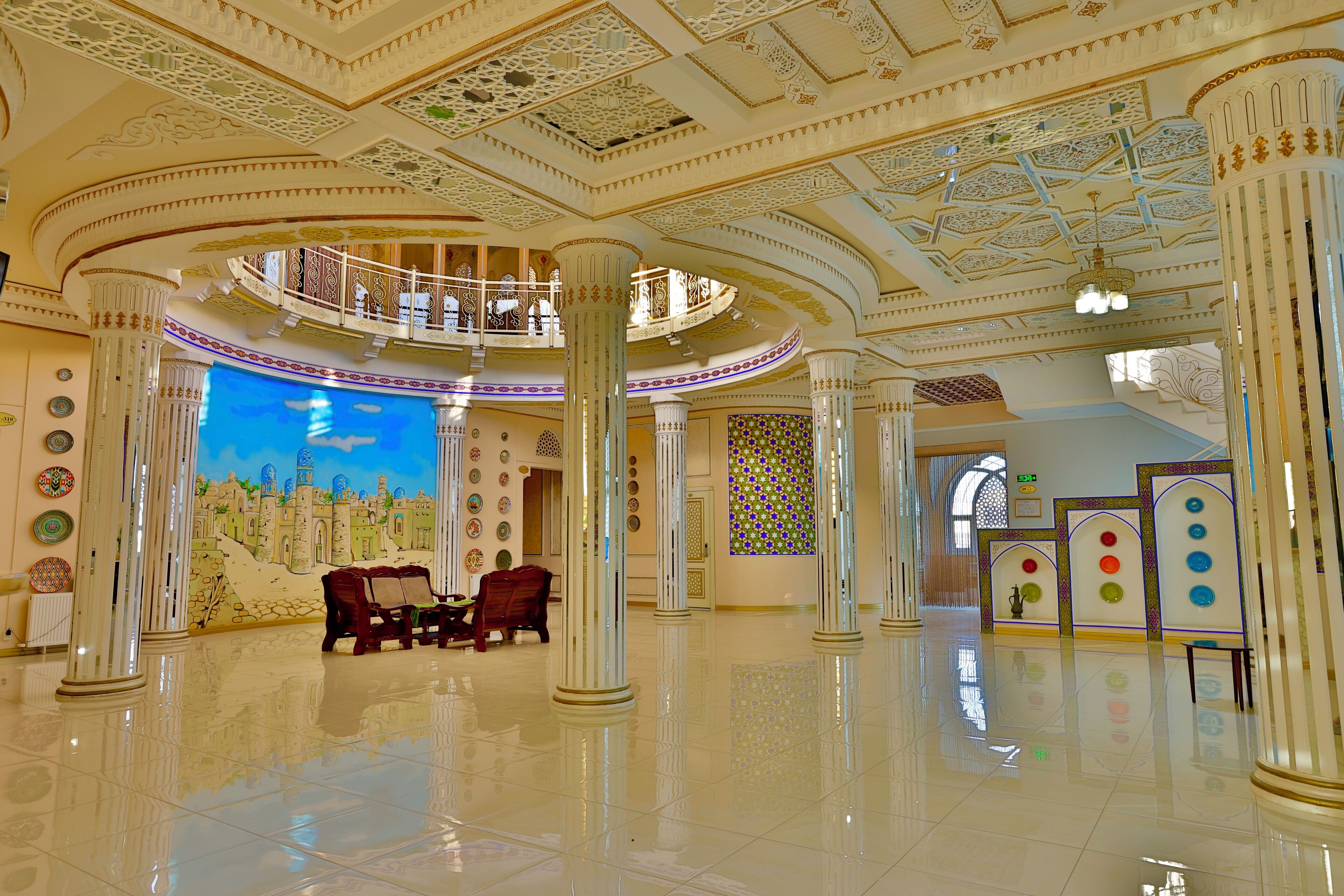 Um hall espaçoso com pé-direito alto, colunas ornamentadas e um grande mural retratando uma cena histórica.