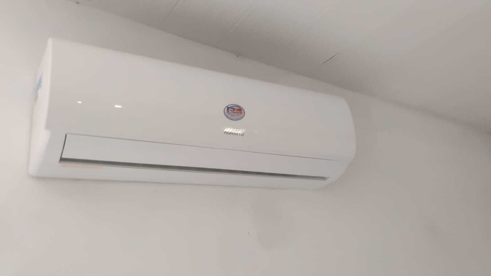 Um aparelho de ar condicionado branco fixado na parede, com painel de controle e logotipo.