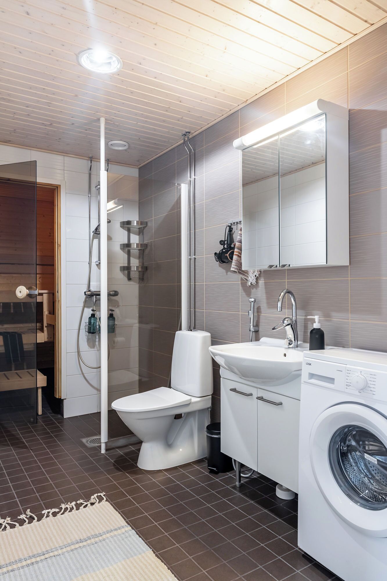 Uma casa de banho moderna com sanita, lavatório e máquina de lavar roupa.