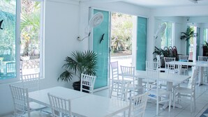 Um quarto claro e arejado, com mobiliário branco e janelas grandes.
