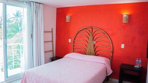 Quarto com cama, mesa de cabeceira, janela com cortinas e parede vermelha.