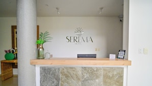 Balcão de recepção com fachada de pedra, logotipo do 'Serema Hotel' e código QR para check-in.