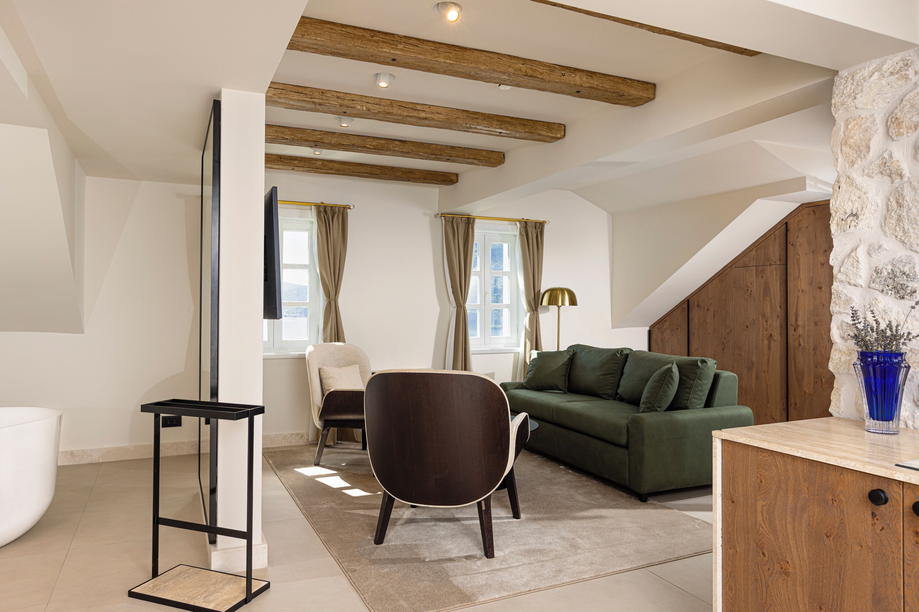 Sala moderna com teto de madeira, sofá verde, cadeira marrom e banheira branca.