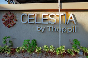 Placa para 'CELESTIA by Thoppil', com um logotipo e vegetação à frente.