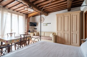 Quarto com uma cama, mesa de jantar com cadeiras, sofá e guarda-roupa.