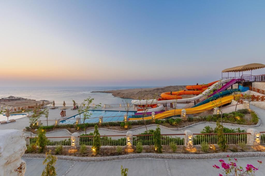Um parque aquático com vários toboáguas, uma piscina e vista para o oceano.