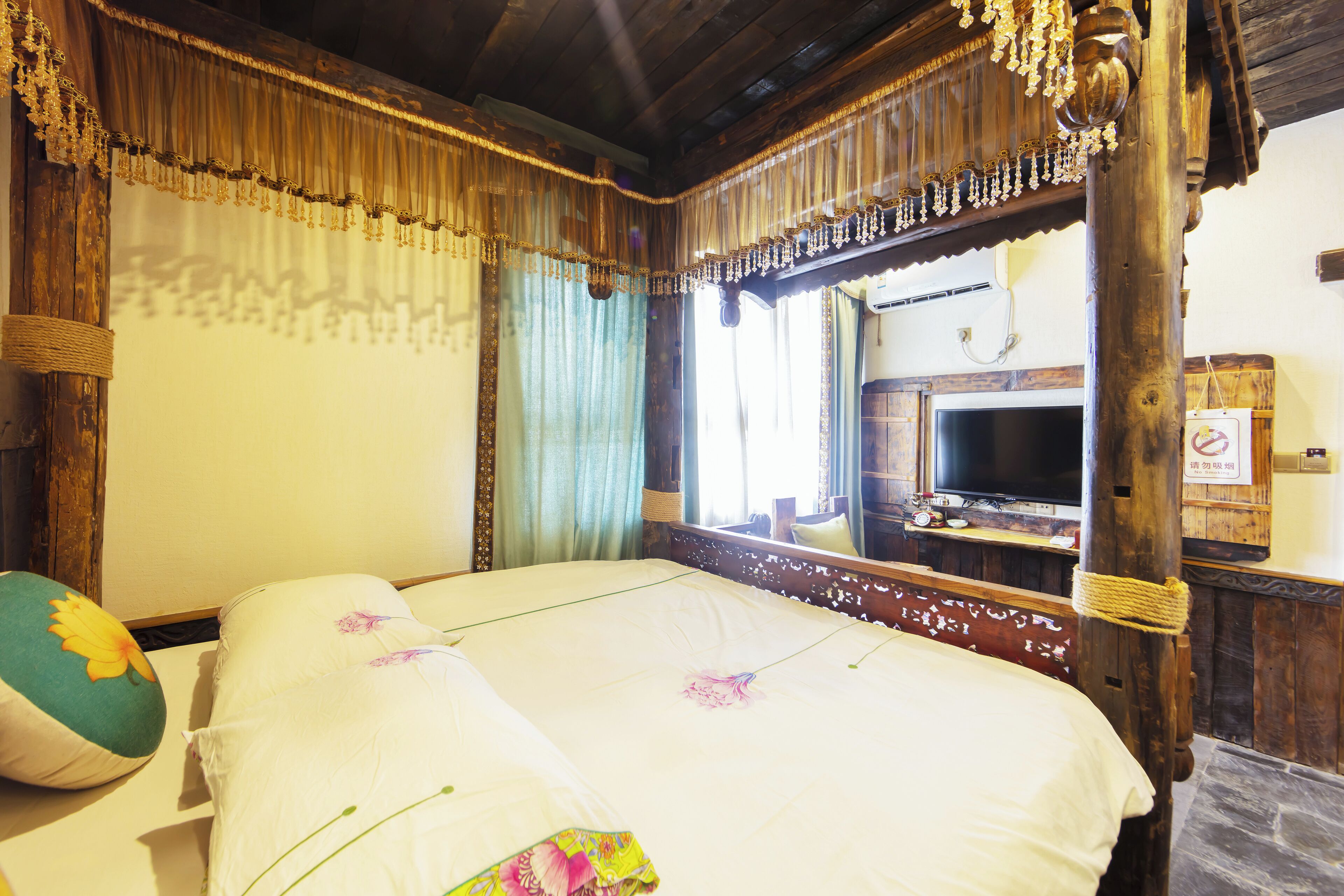 Quarto tradicional com cama, cortinas e televisão.