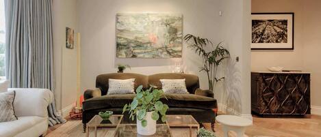 Uma sala de estar com um sofá, uma mesa de centro e um quadro na parede.