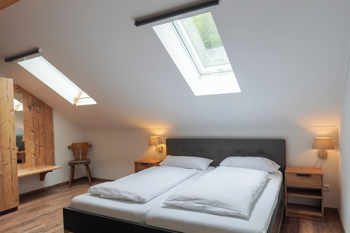 Quarto com uma cama grande, claraboias, vigas de madeira e piso de madeira.