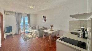 Um apartamento moderno com sala de estar, espaço para refeições e kitchenette.
