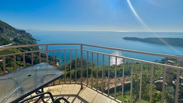 Uma varanda com vista clara para o mar e uma ilha ao longe.