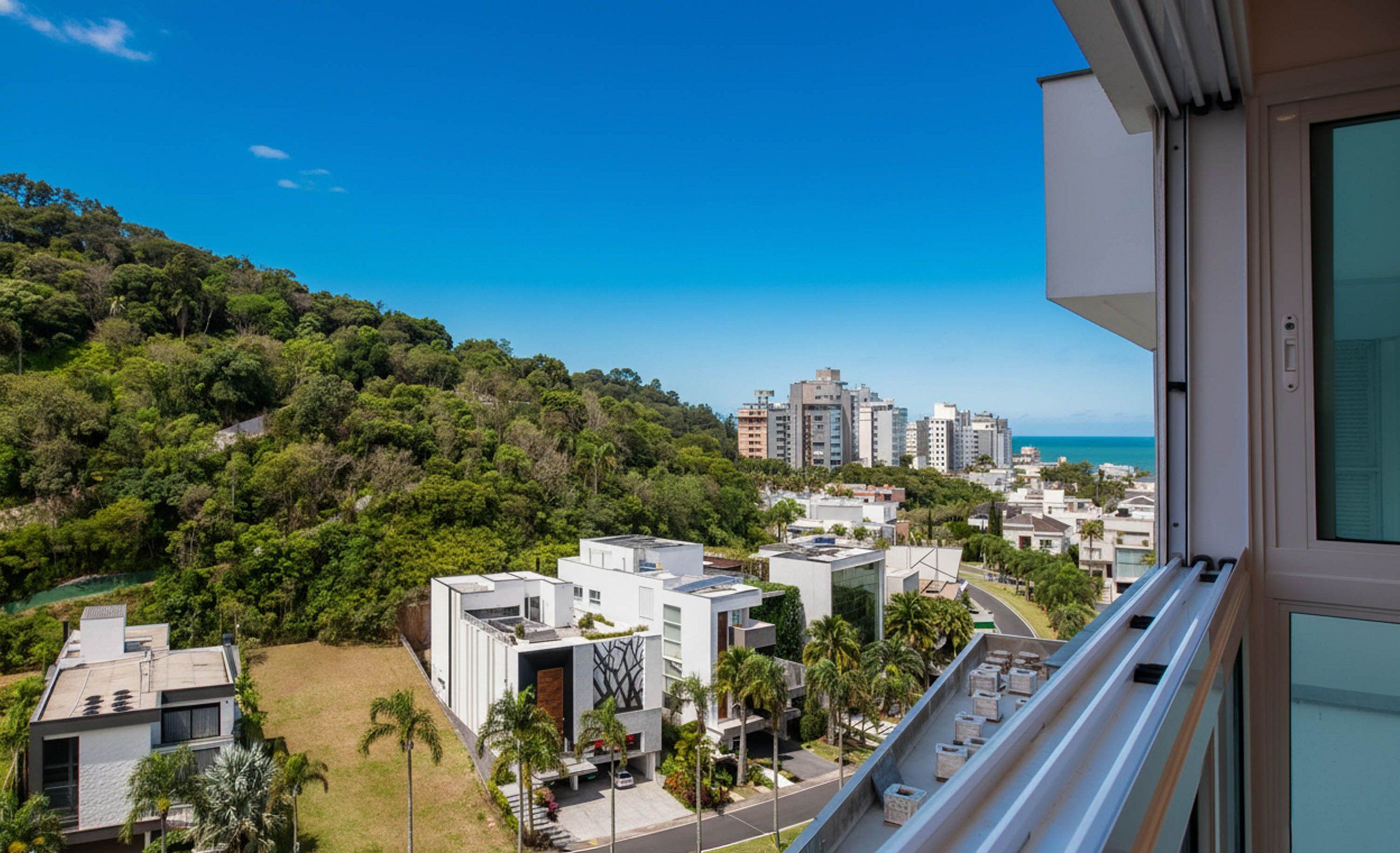 Zona residencial com edifícios modernos, céu claro e vista para o mar.