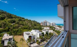 Zona residencial com edifícios modernos, céu claro e vista para o mar.