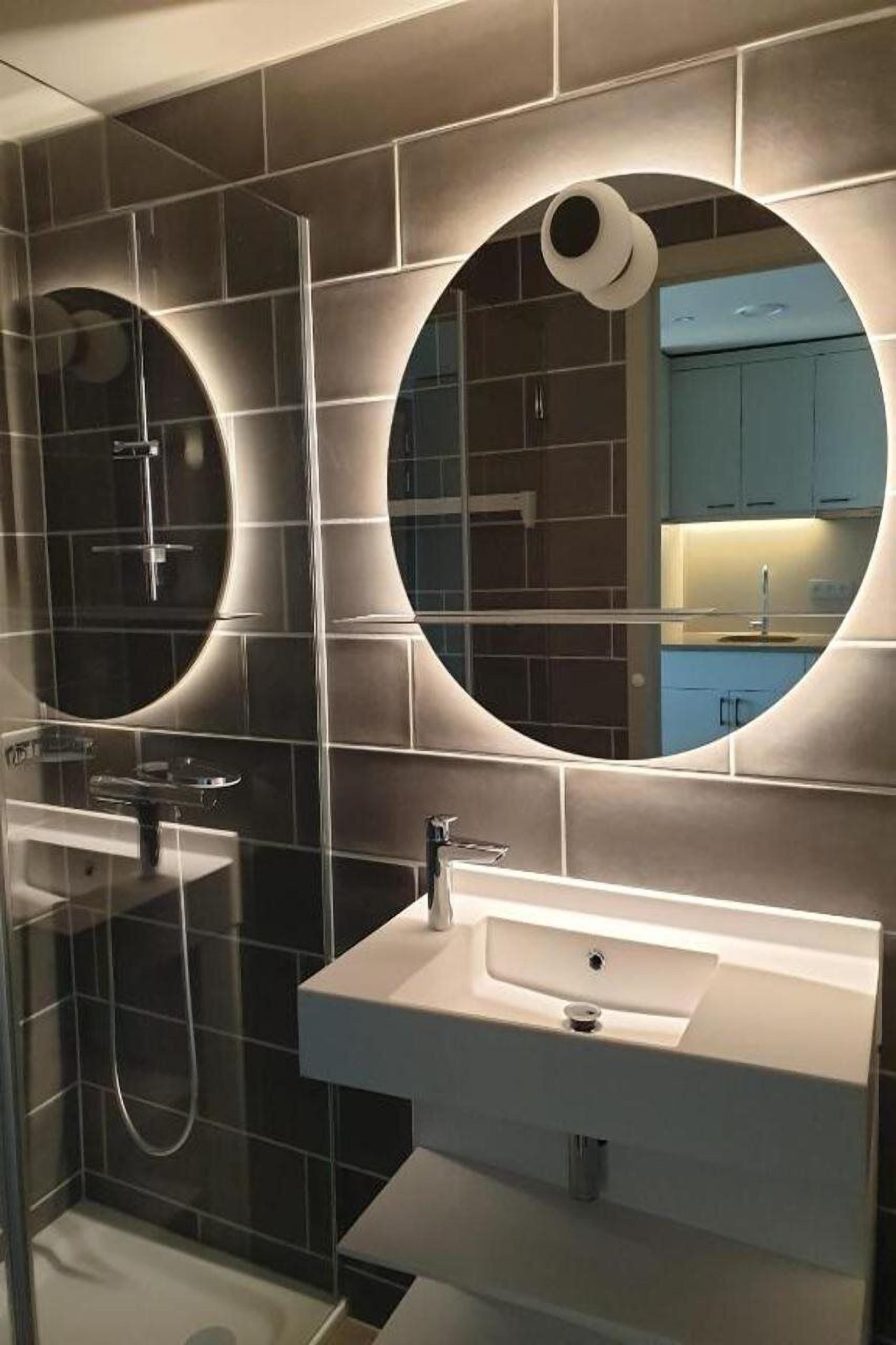 Uma casa de banho moderna com duas lavatórios, chuveiro e sanita.