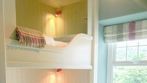 Quarto com beliche, janela e vista para o verde lá fora.