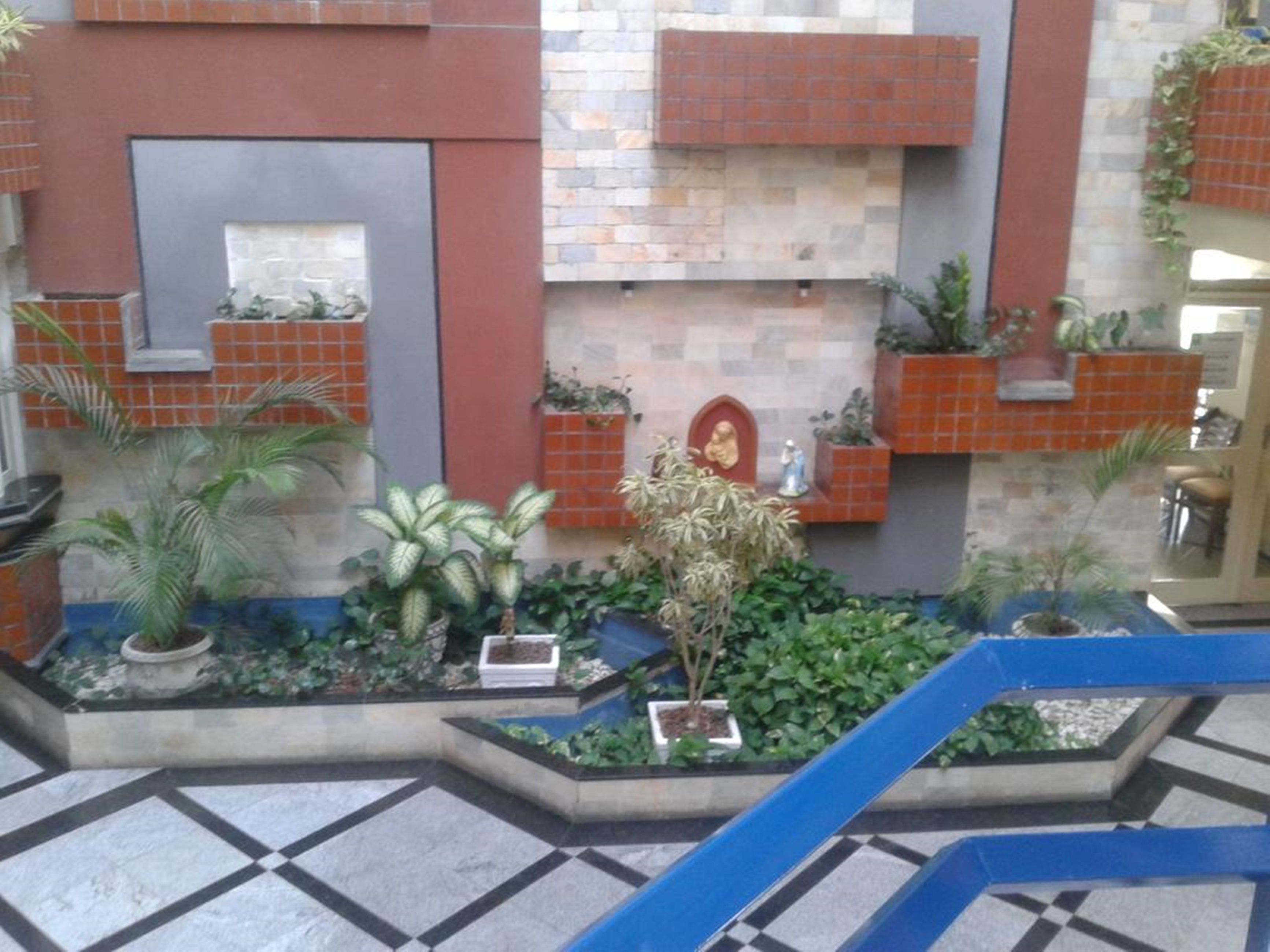 Um edifício com fachada em azulejos, escadaria e diversos vasos de plantas.