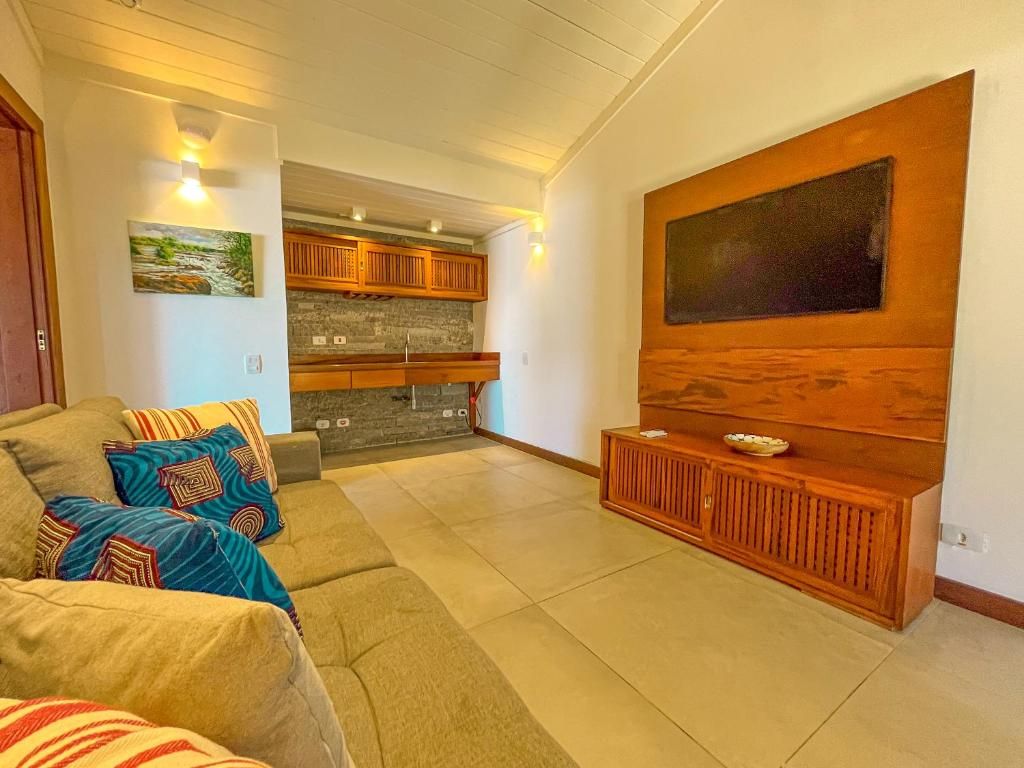 Uma sala de estar com sofá, console de madeira, painel de pedra e uma pintura na parede.