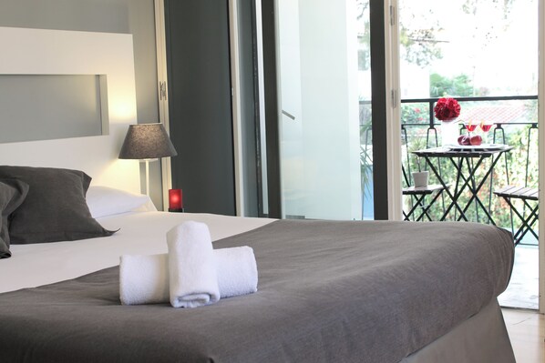 Quarto de hotel com cama, luminária e varanda com mesa e cadeiras.