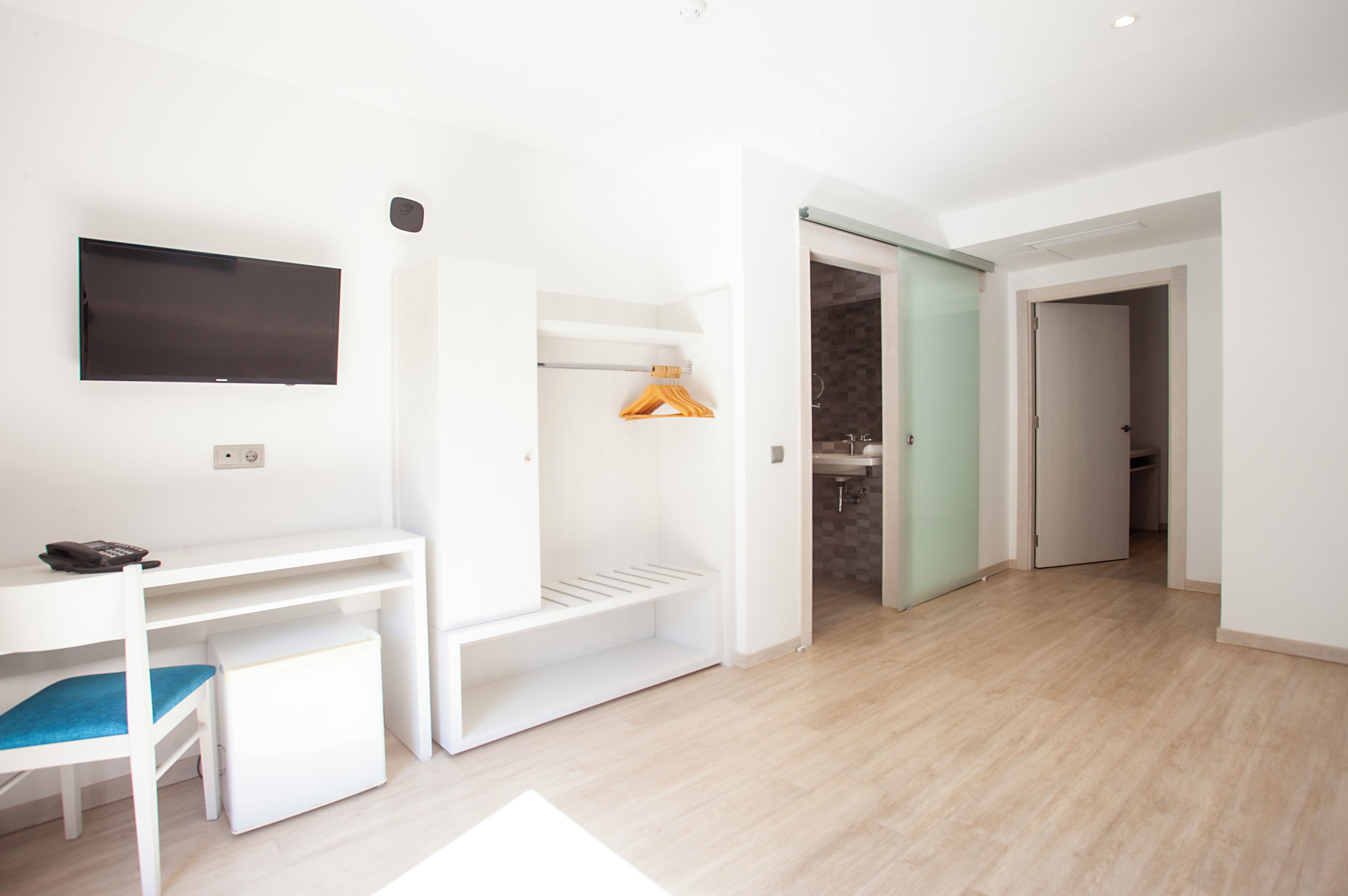 Quarto moderno e minimalista com escrivaninha, cadeira e guarda-roupa com prateleira suspensa.