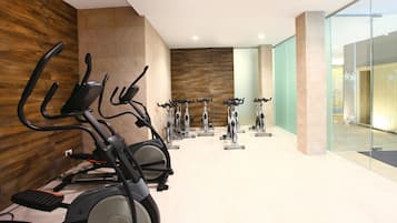 Uma academia moderna com bicicletas ergométricas e elípticos, paredes de madeira e uma porta de vidro que dá para um ambiente claro.