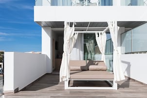 Uma área de estar moderna ao ar livre, com um banco acolchoado e um toldo.