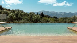 Piscina límpida com vista para montanhas e árvores ao fundo.