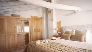 Quarto com uma cama grande, guarda-roupa de madeira e mesa de cabeceira com luminária.