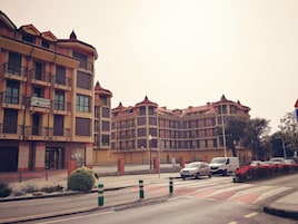 Um edifício residencial de vários andares, com varandas e portão.