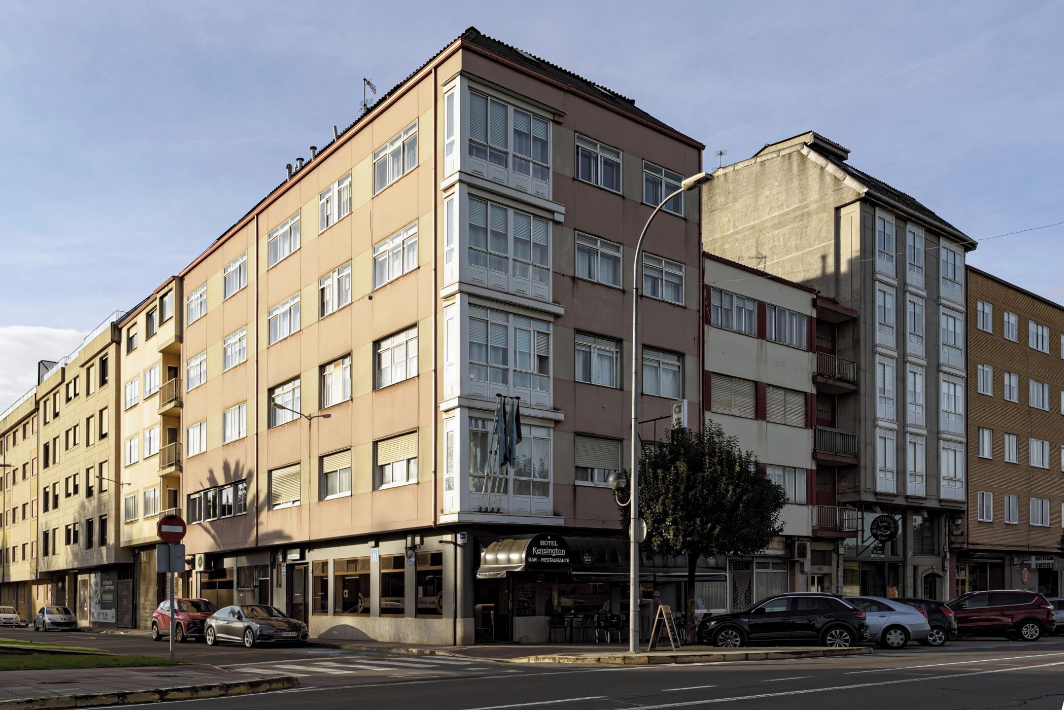Um hotel com vários andares, fachada plana, grandes janelas e um restaurante no térreo.
