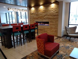Uma área de bar com banquetas, lareira e um tapete estampado.