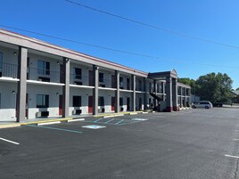 Um motel com vários andares, uma galeria coberta e estacionamento.