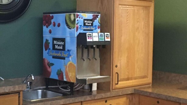Cozinha com dispensador de suco de frutas, pia e armários de madeira.