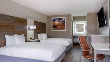 Quarto de hotel com duas camas, uma escrivaninha, uma cadeira, uma televisão, um quadro e um espelho de banheiro.