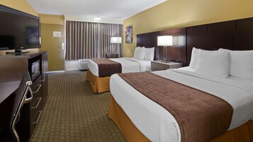 Quarto de hotel com duas camas, televisão, escrivaninha e cadeira.