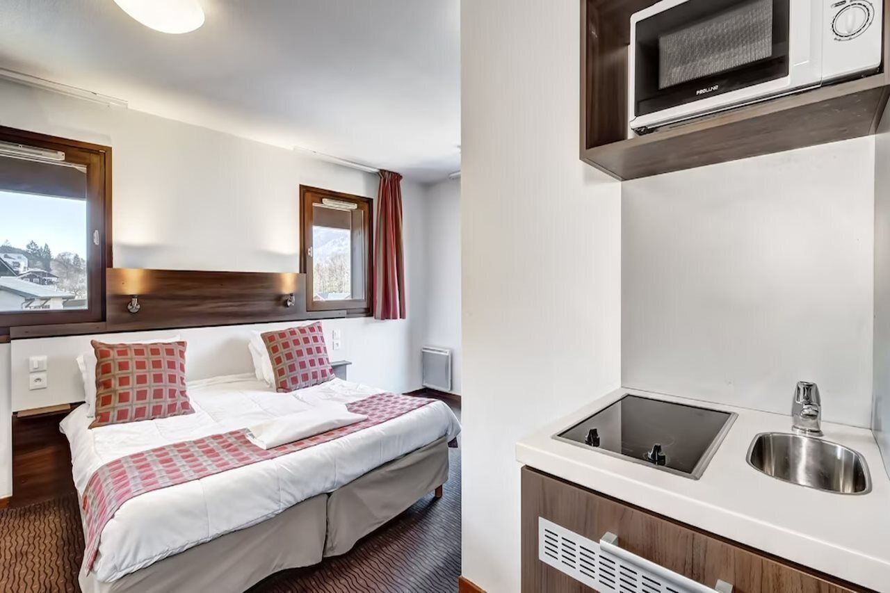 Quarto de hotel com cama, janela com vista, micro-ondas e pia.