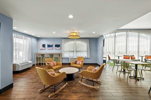 Uma área de estar moderna com uma mesa redonda central, cadeirões de balanço amarelos e uma sala de jantar com mesas e cadeiras.