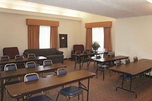 Uma sala de conferência com mesas, cadeiras, um sofá e cortinas.