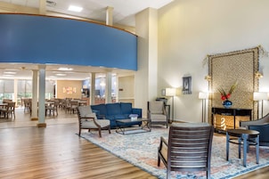 Um hall de hotel com uma parede azul de destaque, um tapete estampado e uma lareira decorada.