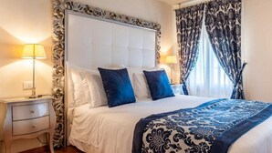 Quarto de hotel com uma cama grande, duas luminárias de cabeceira, uma cabeceira decorativa e cortinas estampadas.