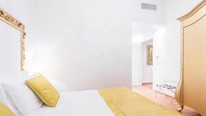 Quarto de hotel com cama, manta amarela, espelho e guarda-roupa.