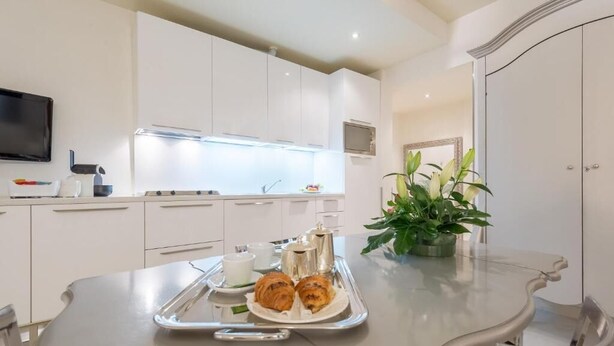 Cozinha moderna com armários brancos, bancada de aço inoxidável e uma bandeja com doces e uma xícara de café.